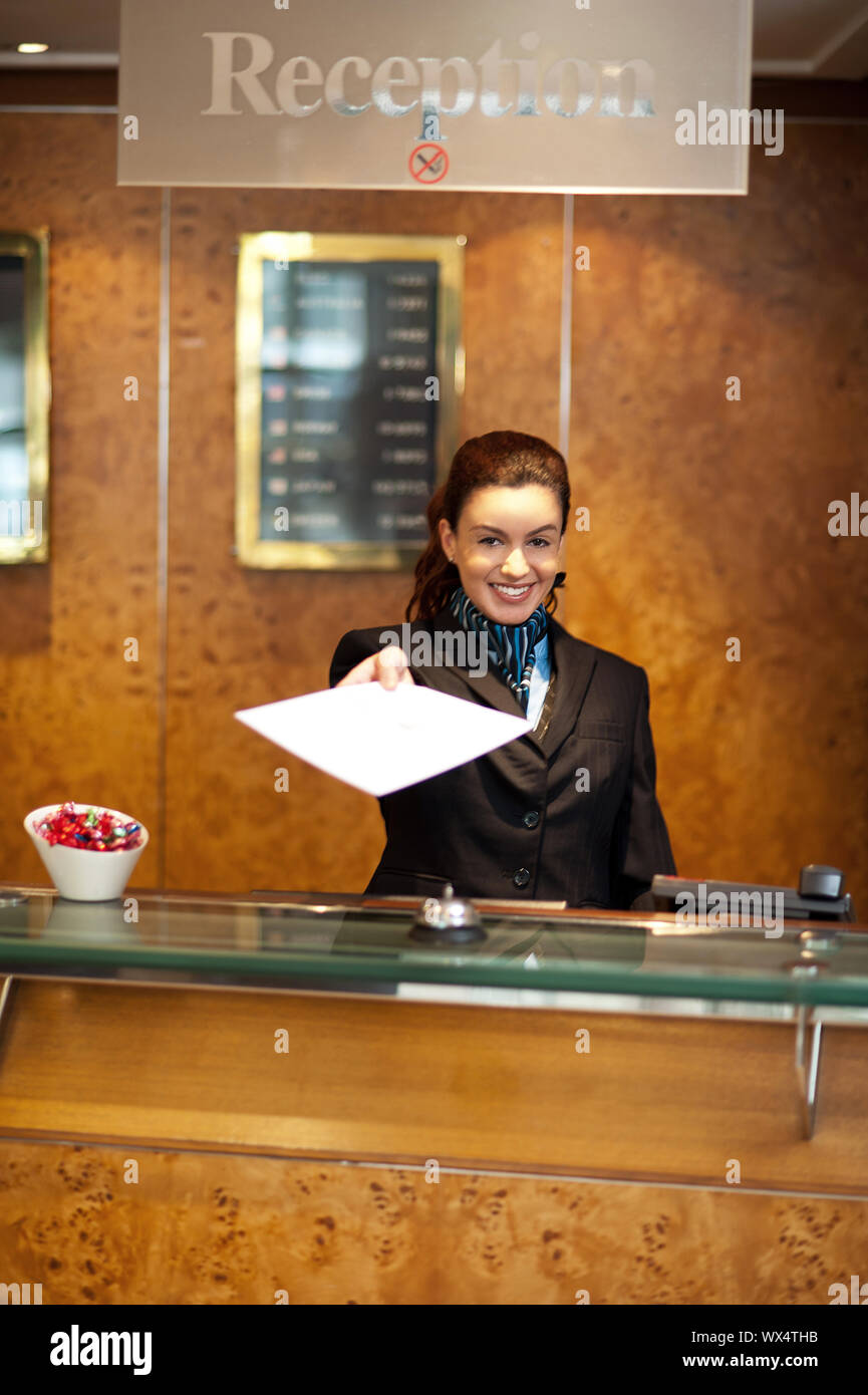 Female receptionist handing over check-out papers along with bill to ...