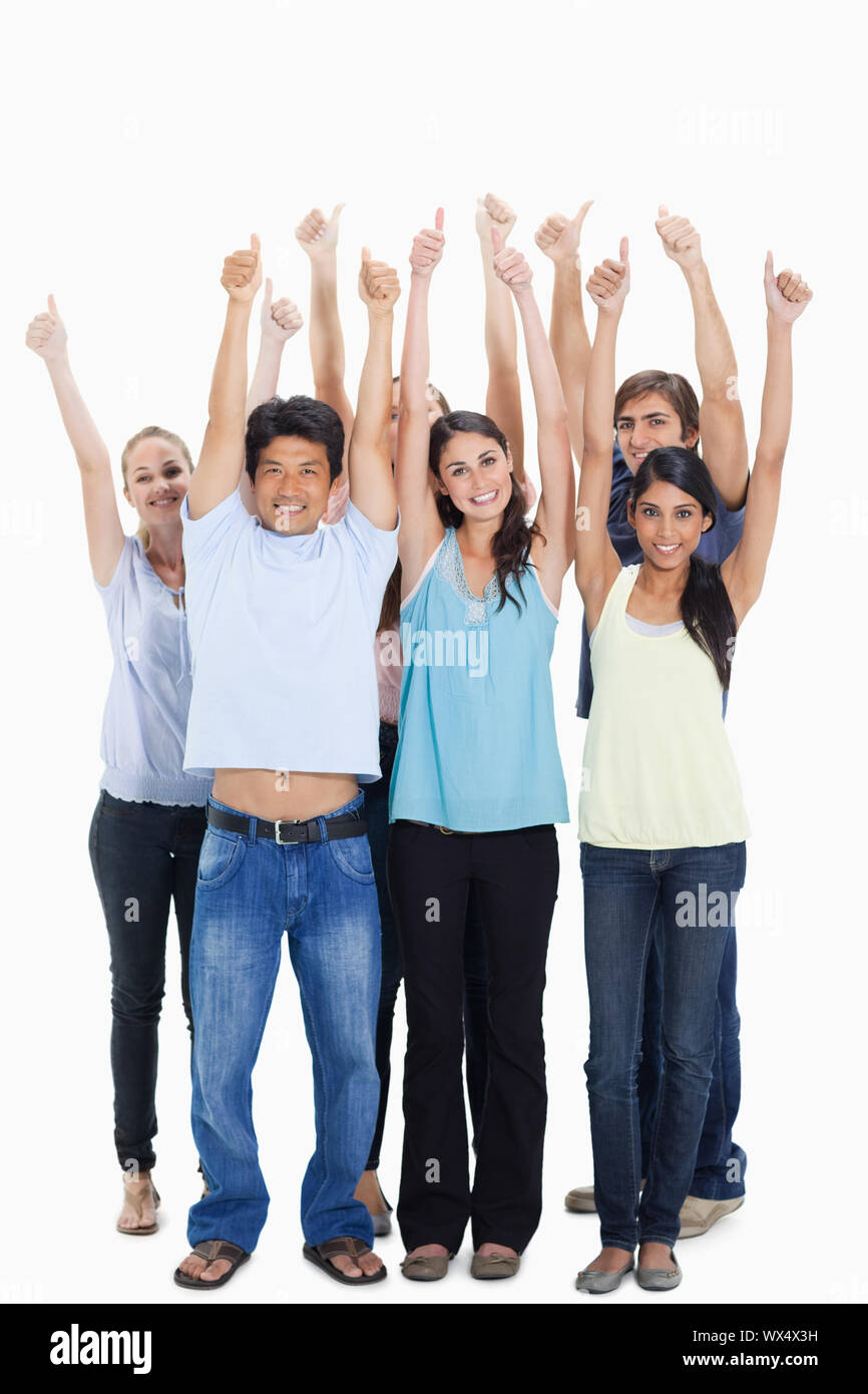 People smiling together raising their arms with their thumbs-up against ...