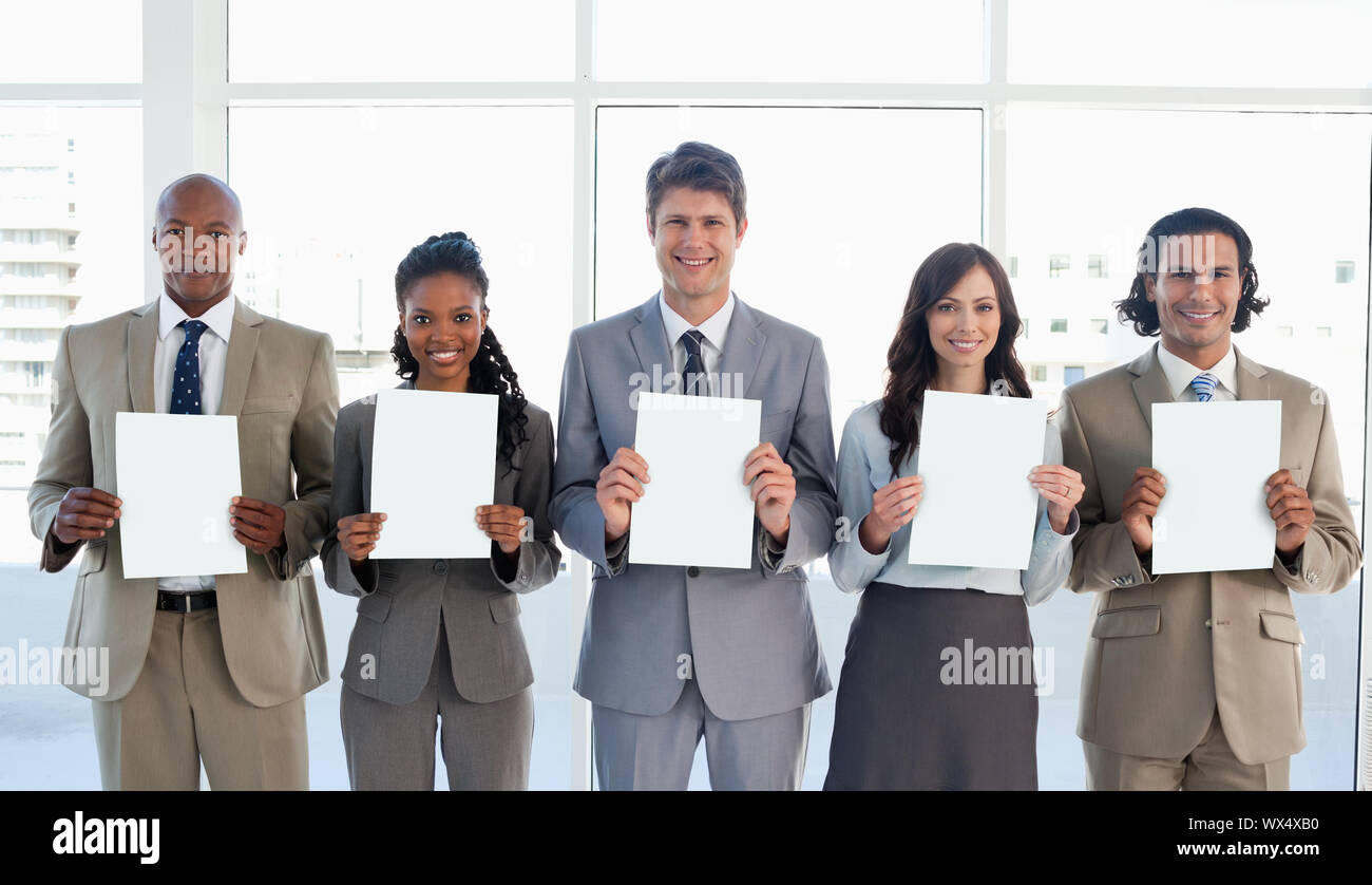 Business team standing upright side by side while showing blank sheets ...