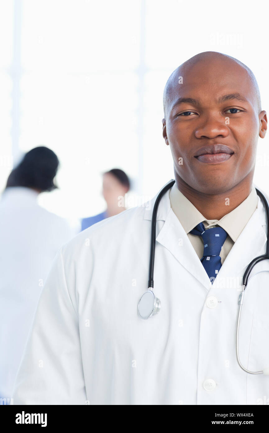 Young doctor grinning in front of his medical team with a confident ...