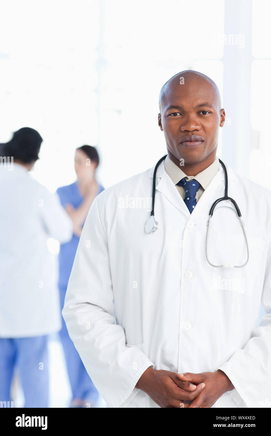 Doctor standing upright with his hands crossed with his medical team ...