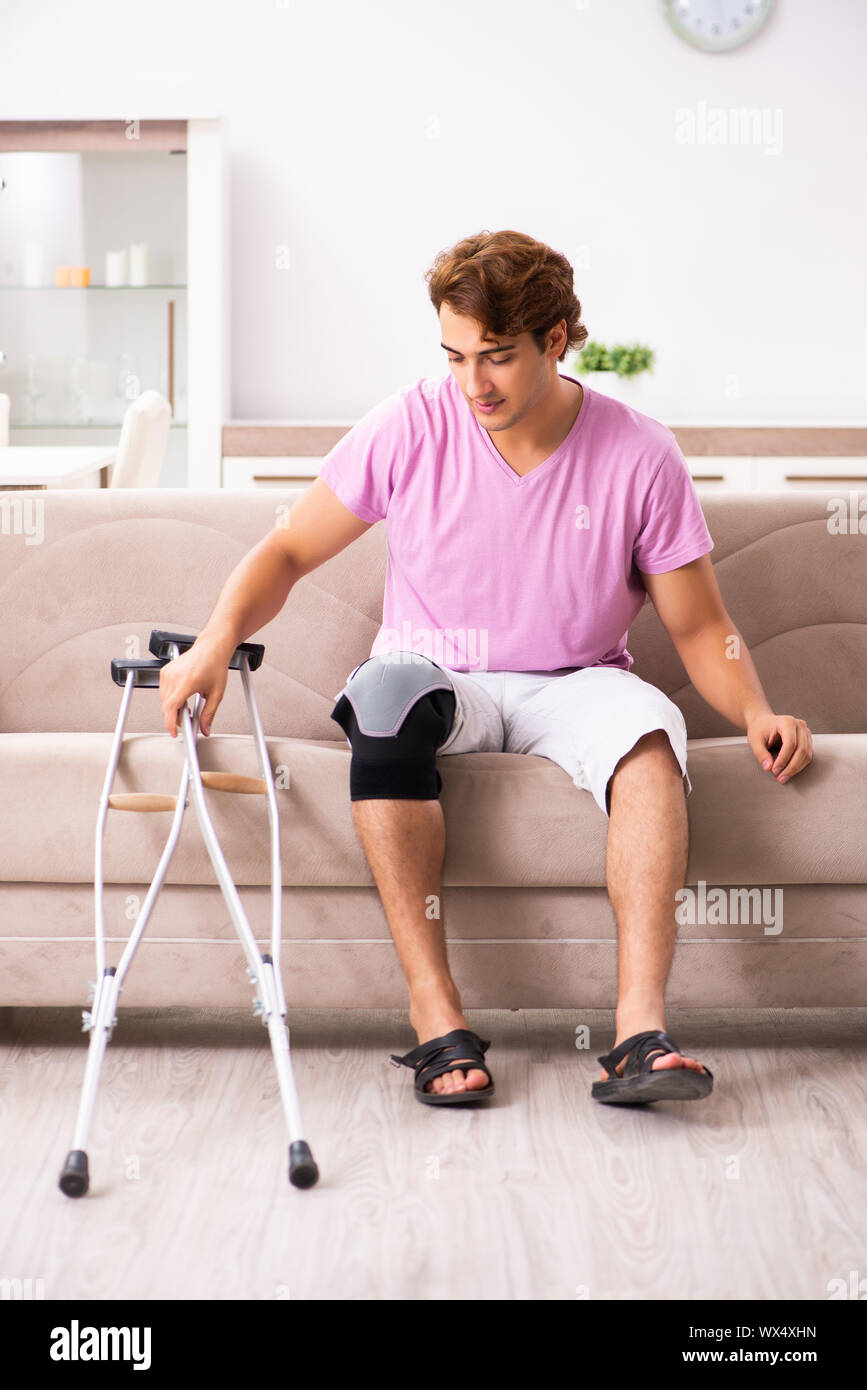 Young man with injured knee recovering at home Stock Photo - Alamy