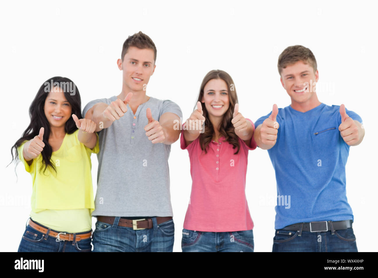 A smiling group of friends give a thumbs up while looking at the camera ...