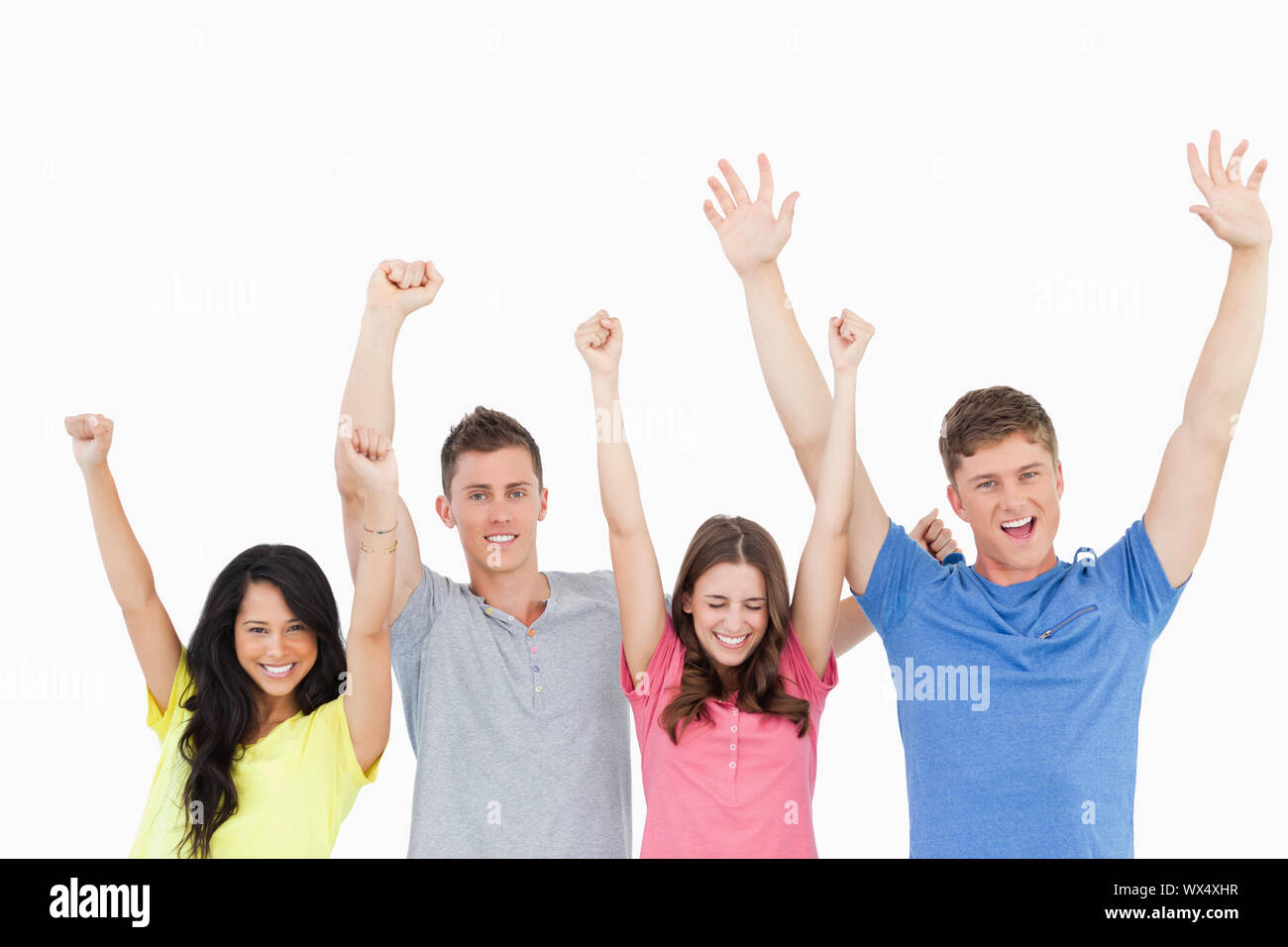 Four friends celebrating together with their hands in the air as they ...
