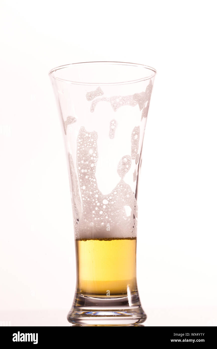 Almost empty glass of beer against a white background Stock Photo - Alamy