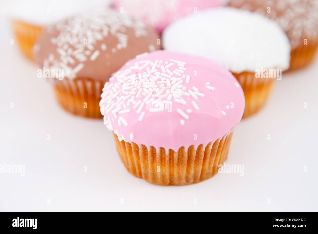 Close up on a pyramid of muffins with icing sugar against a white ...