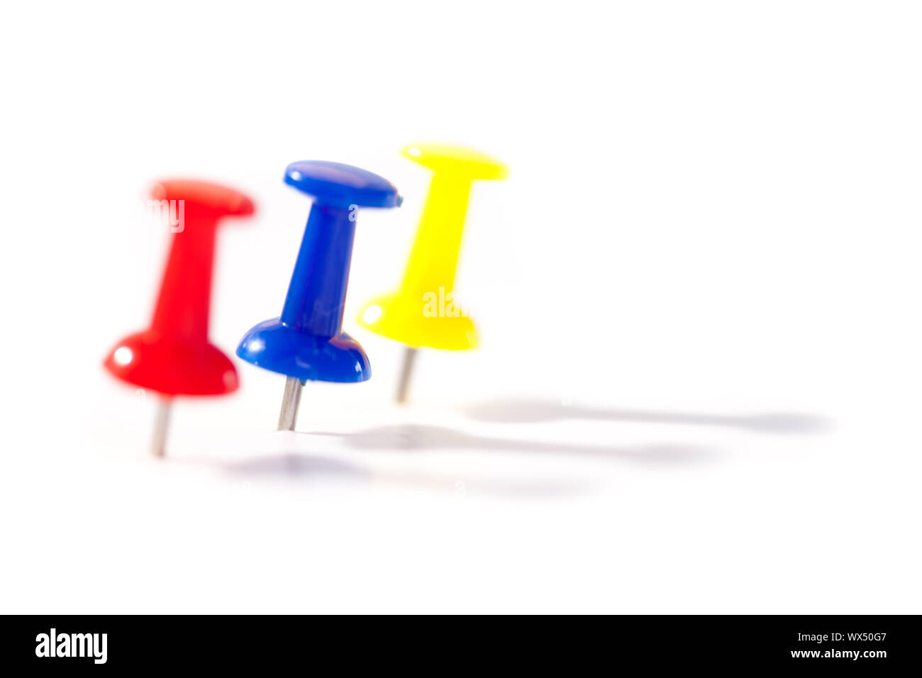 Three blurred push pins against a white background Stock Photo - Alamy