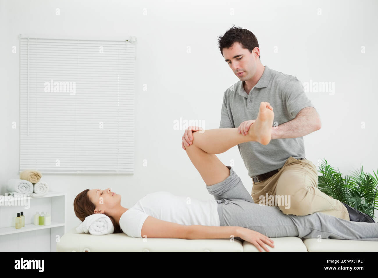 Chiropractor stretching the leg of his patient while holding it in a ...