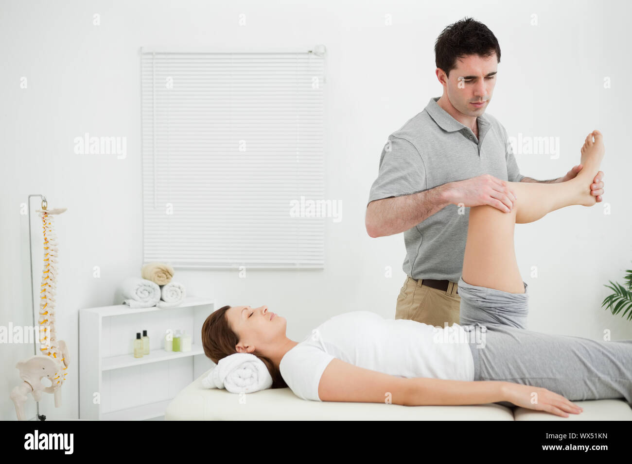 Doctor examining the leg of his patient while raising it in a medical ...