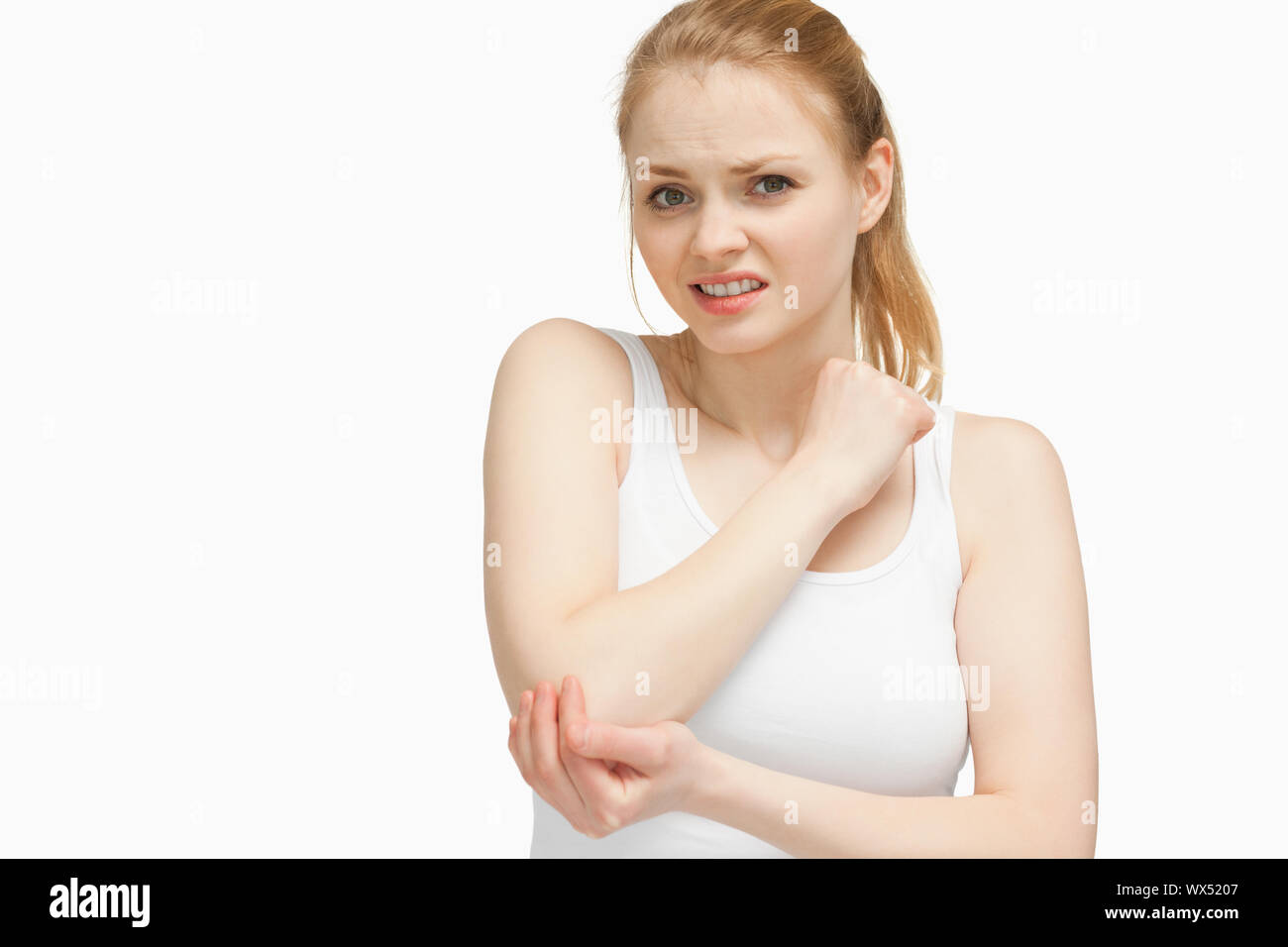 Fair-haired woman touching her elbow Stock Photo - Alamy