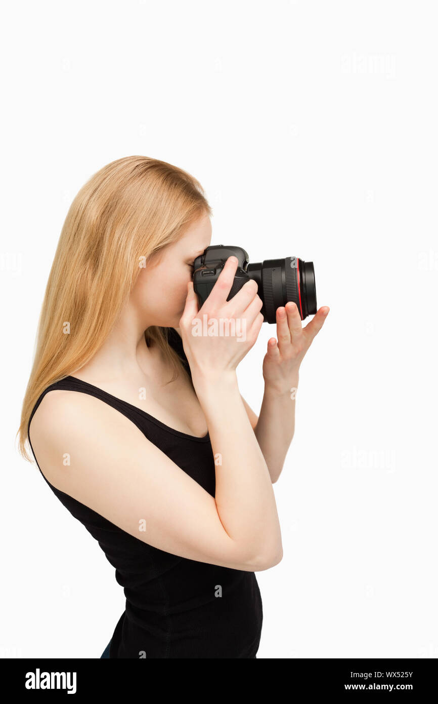 Blonde-haired woman aiming with a camera against white background Stock ...
