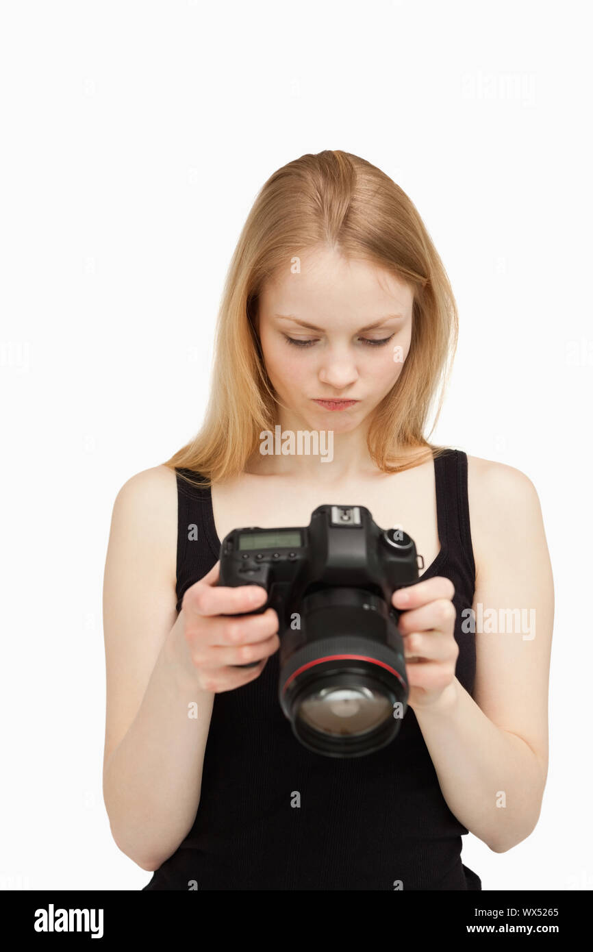 Woman looking at the screen of her camera against white background ...
