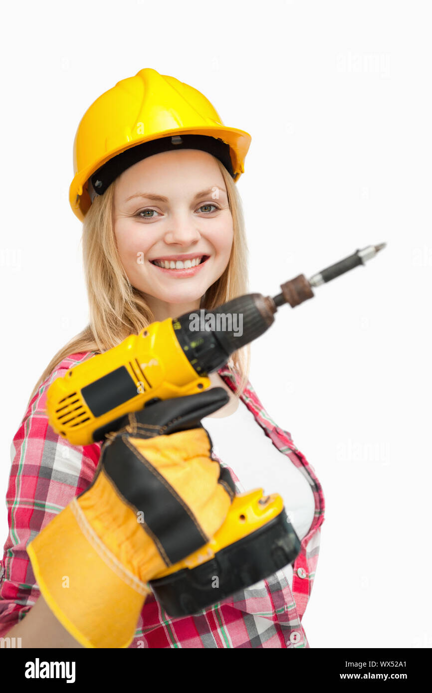 Woman smiling while holding an electric screwdriver against white ...