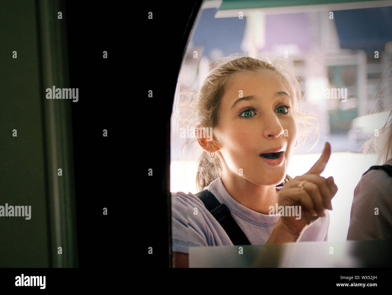 Teenage girl pointing through a window with a surprised look Stock ...
