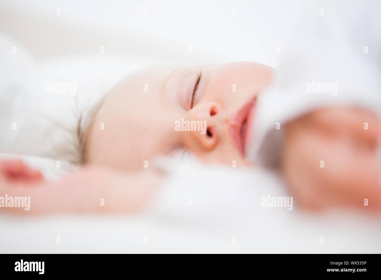 Baby falling asleep while extending her arms in a bedroom Stock Photo ...