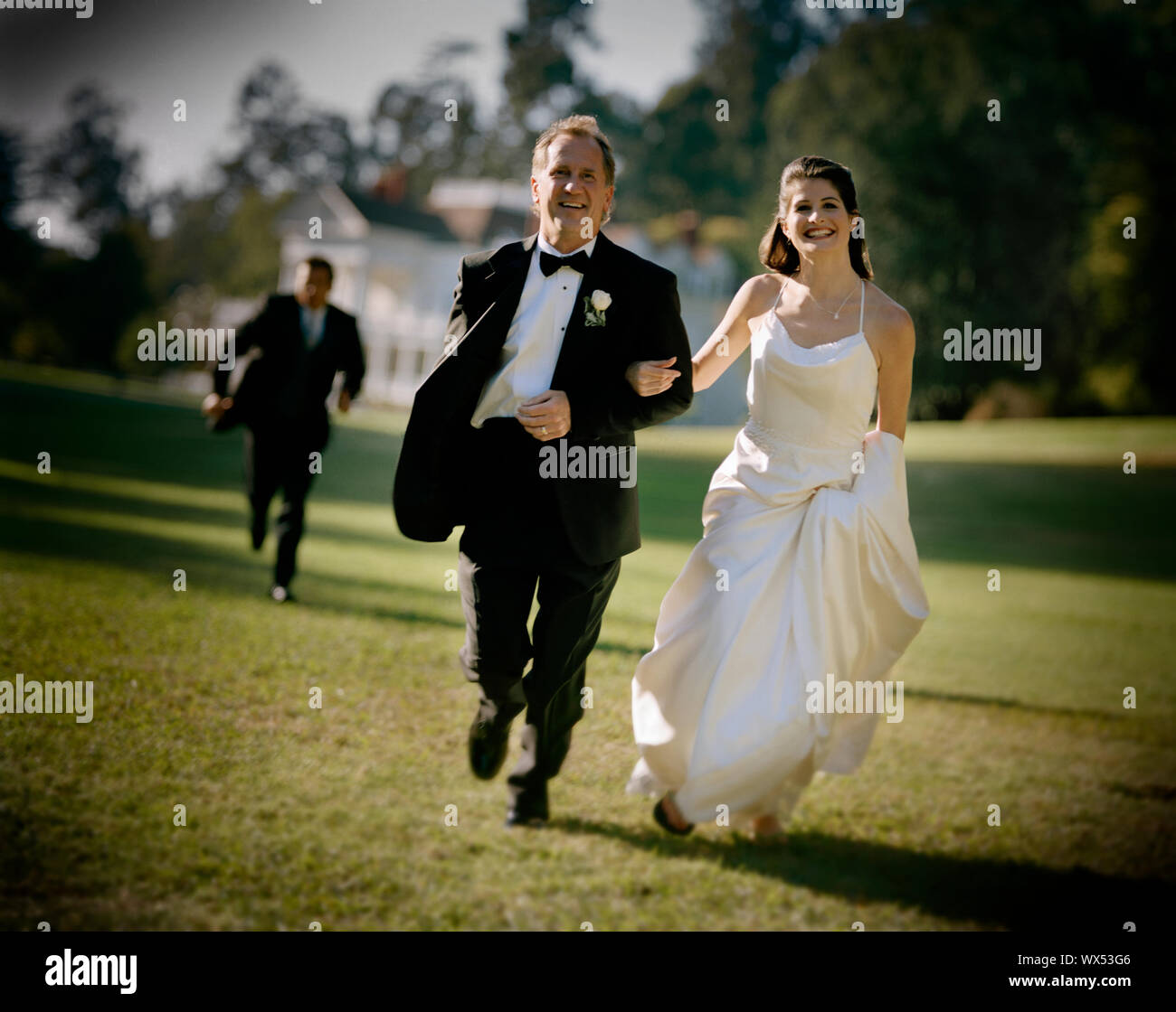 An ecstatic couple running together on their wedding day Stock Photo ...
