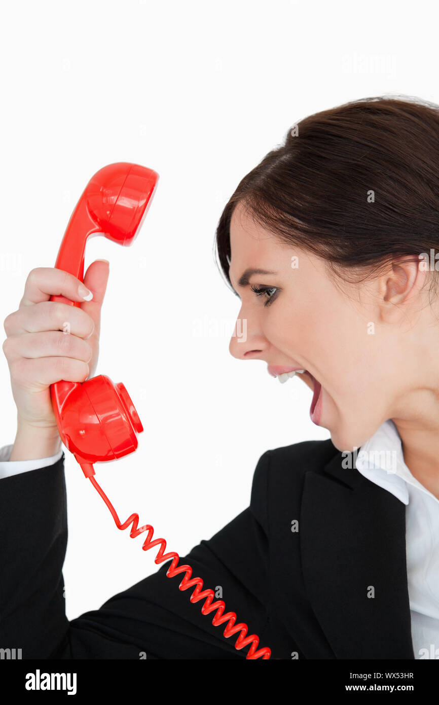 Woman in suit screaming on a red dial telephone against white ...