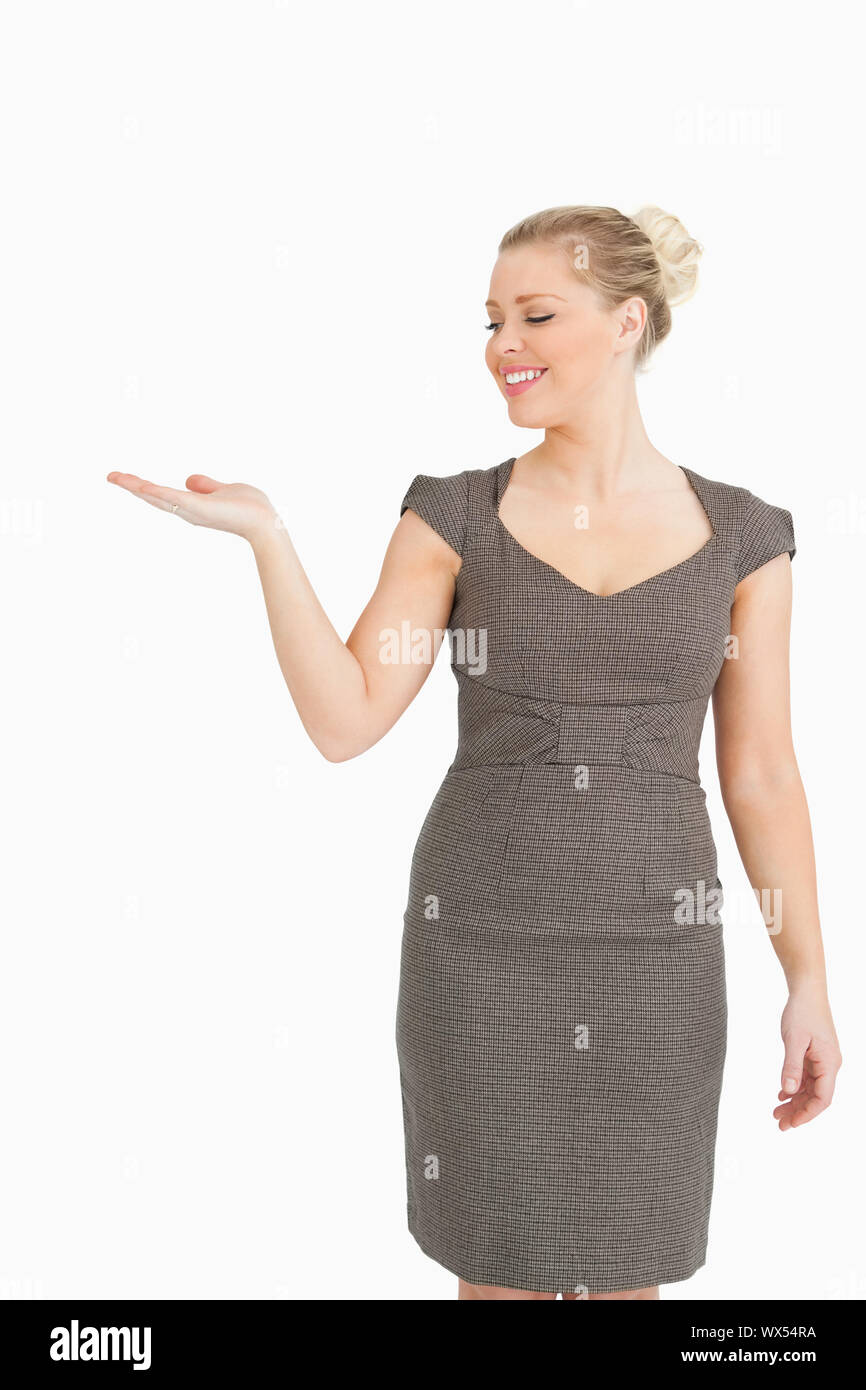 Woman smiling presenting something with her hand against white ...