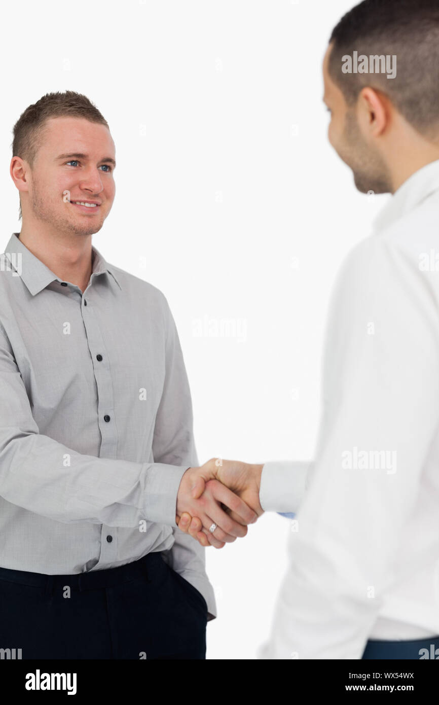 Smiling men shaking hands against a white background Stock Photo - Alamy