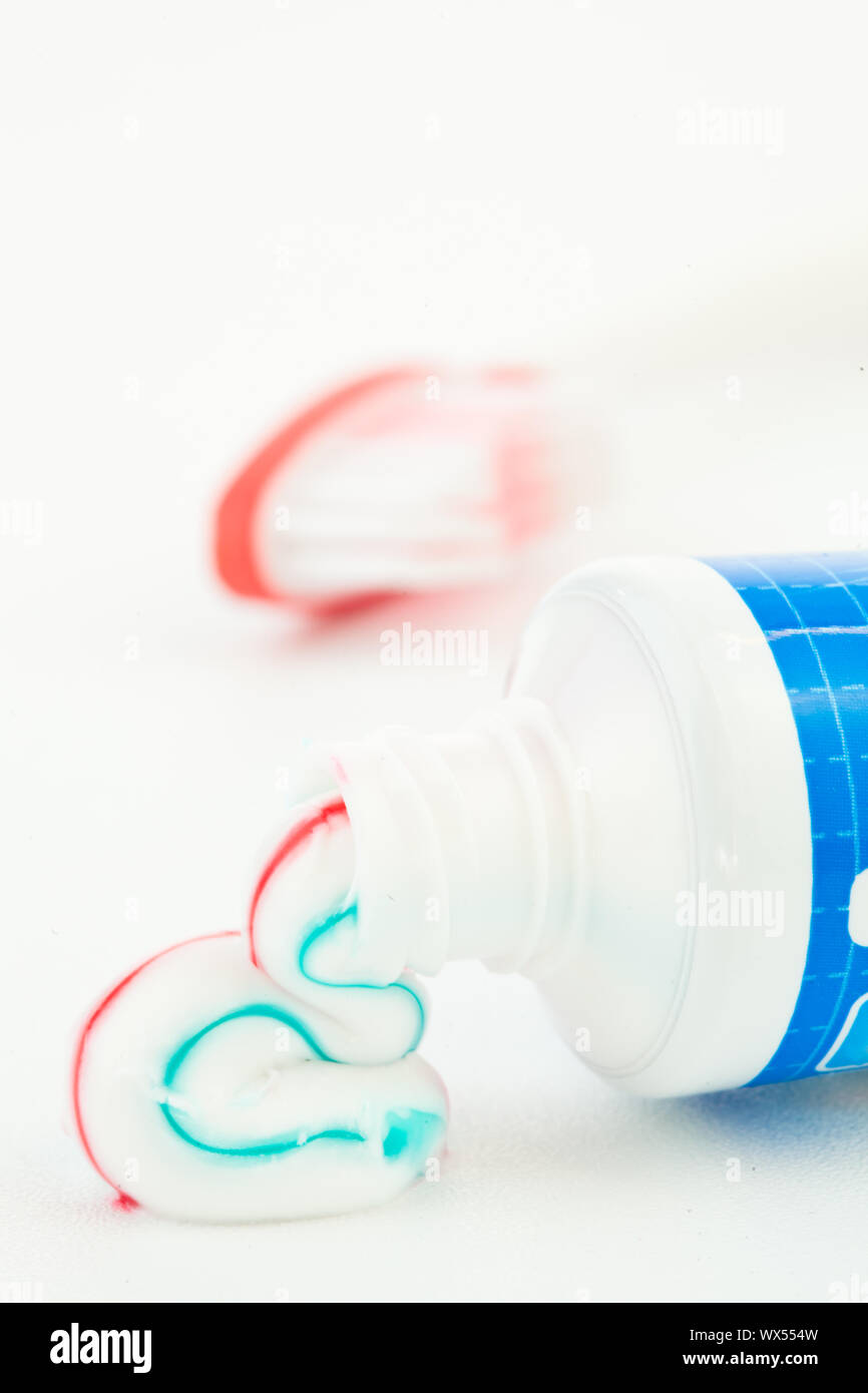 Blue tube of toothpaste next to a toothbrush against white background ...