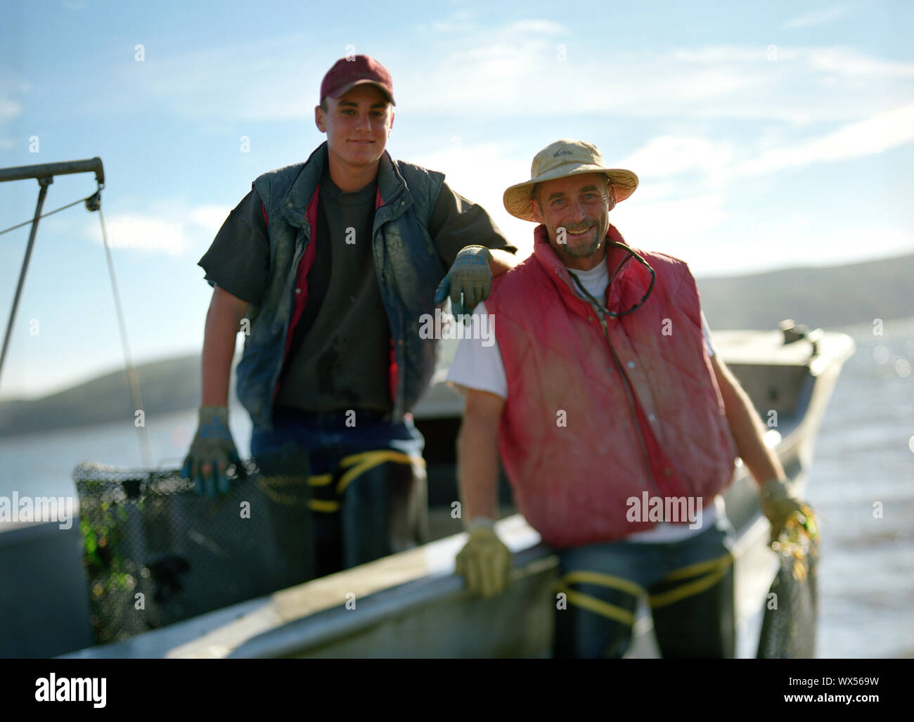 Front view of two men standing beside a boat Stock Photo - Alamy