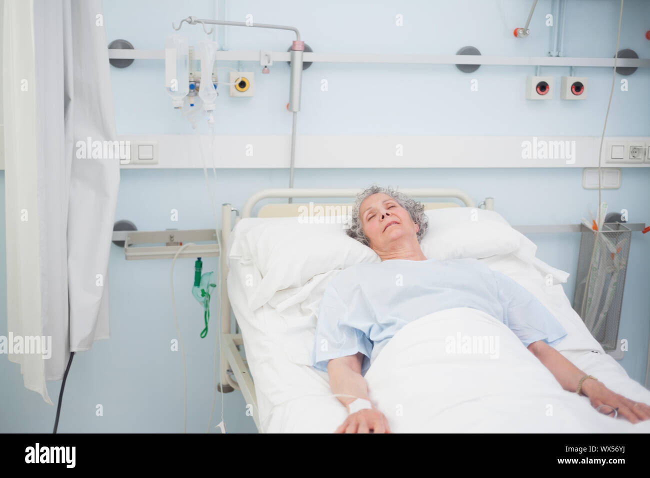 Elderly patient sleeping on a medical bed in hospital ward Stock Photo ...