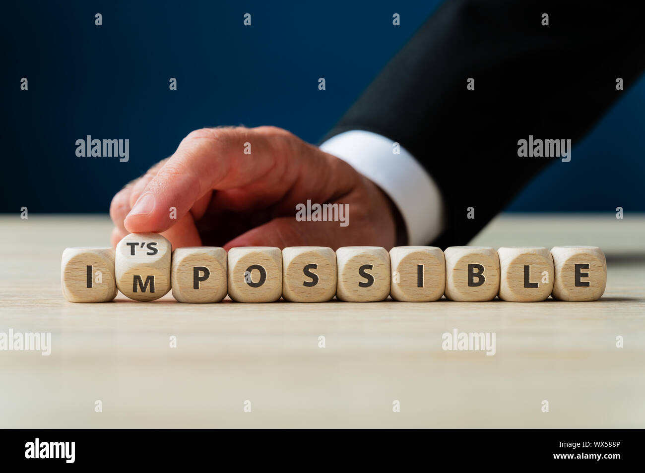 Word impossible spelled on wooden cubes with male finger flipping ...