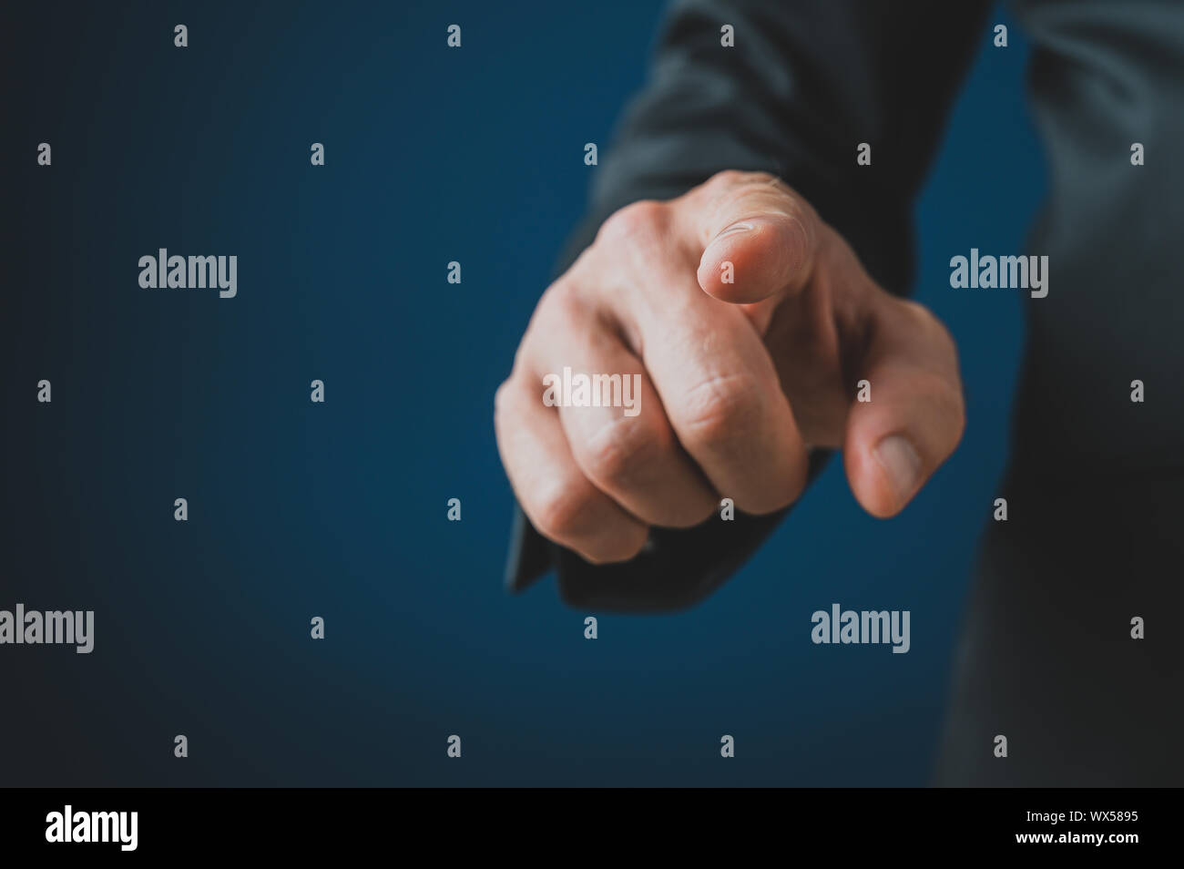Businessman pointing his finger at you. Over navy blue background with ...