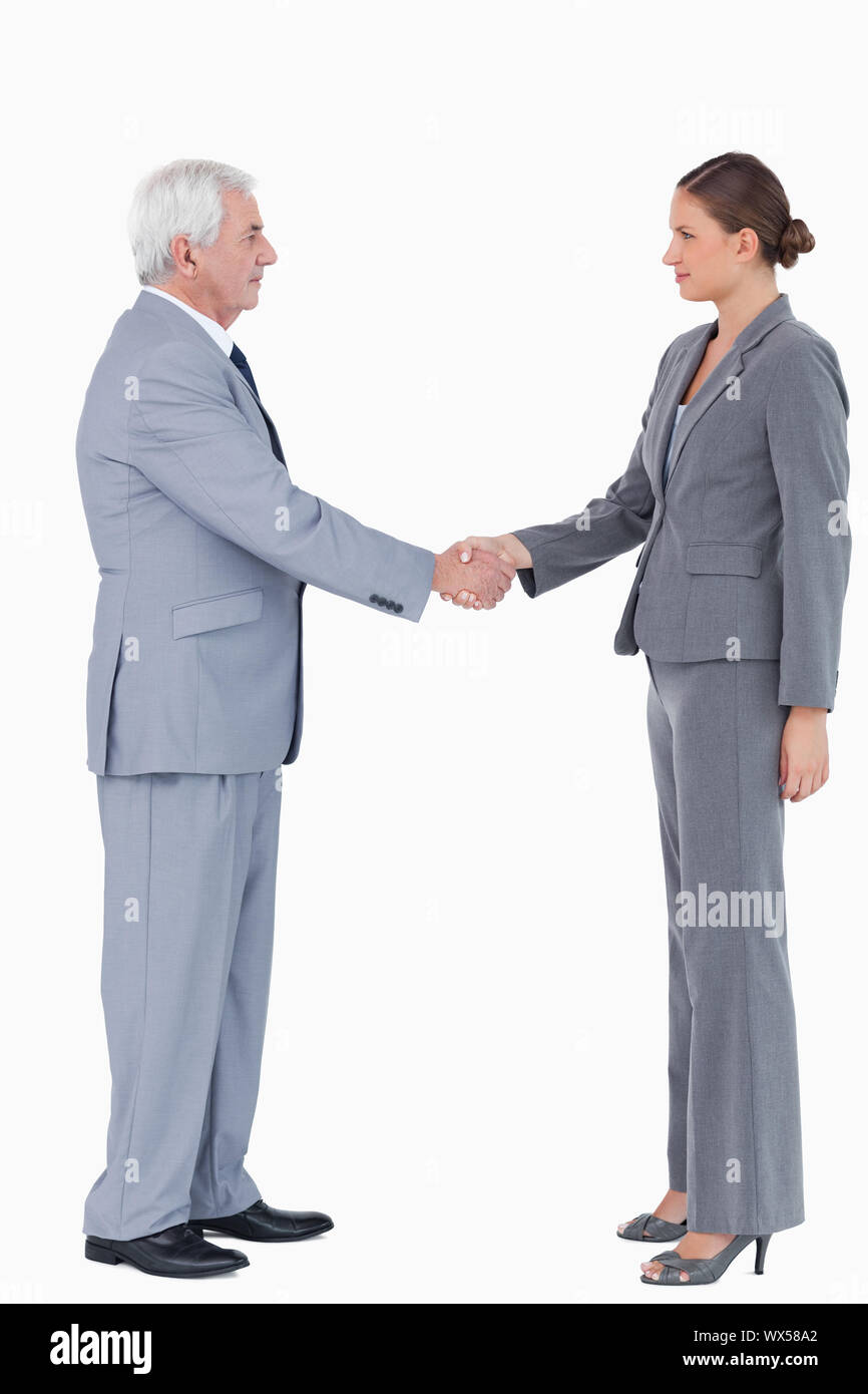 Side view of businesspartner shaking hands against a white background ...