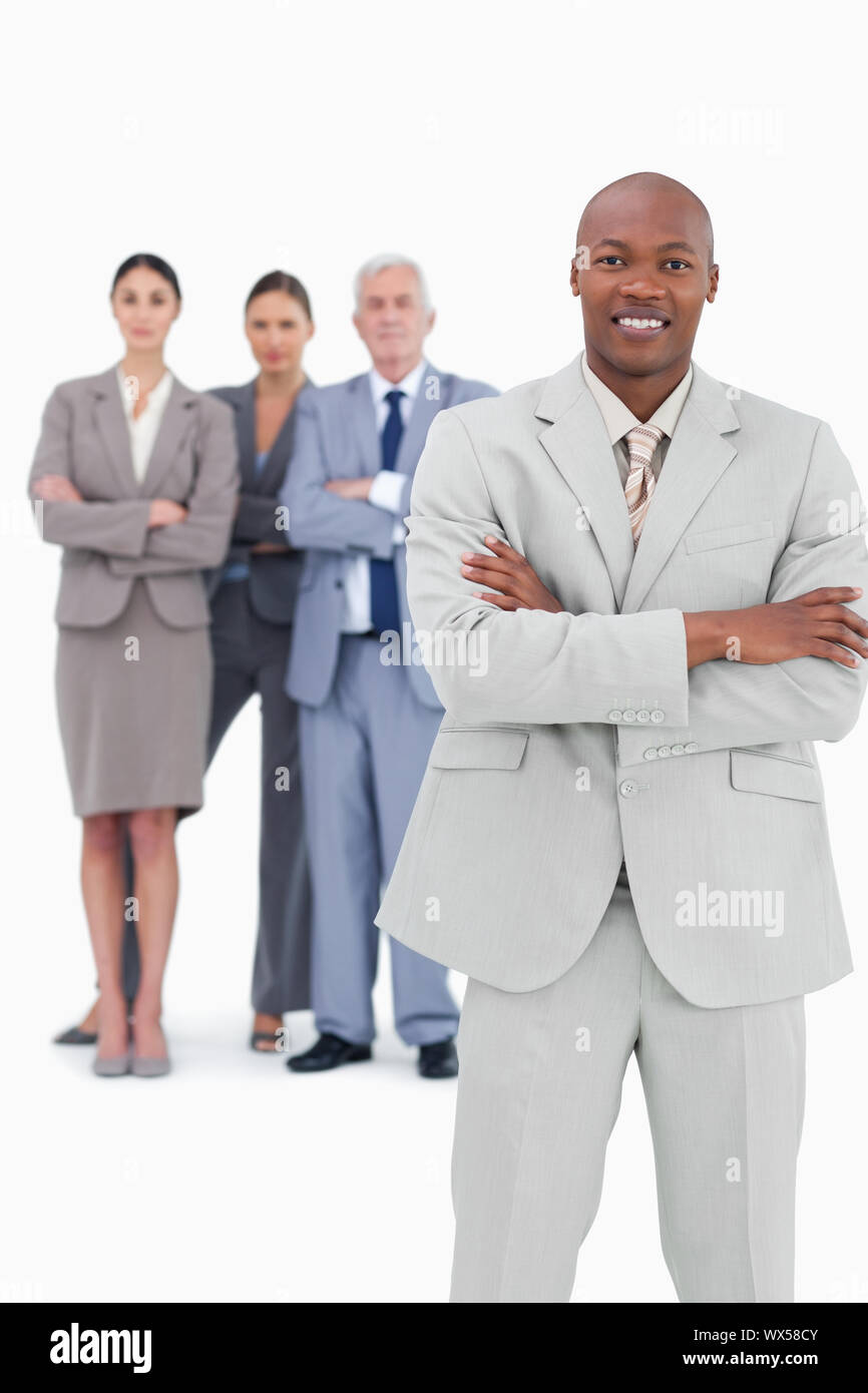 Smiling tradesman with arms folded and team behind him against a white ... Smiling tradesman with arms folded and team behind him against a white ...