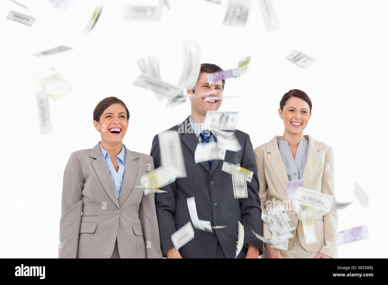 Money dropping down on smiling businessteam against a white background ...