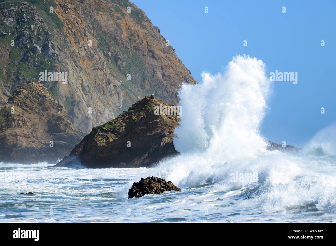 Large breaker crashing against rocks and splashing high into the air ...