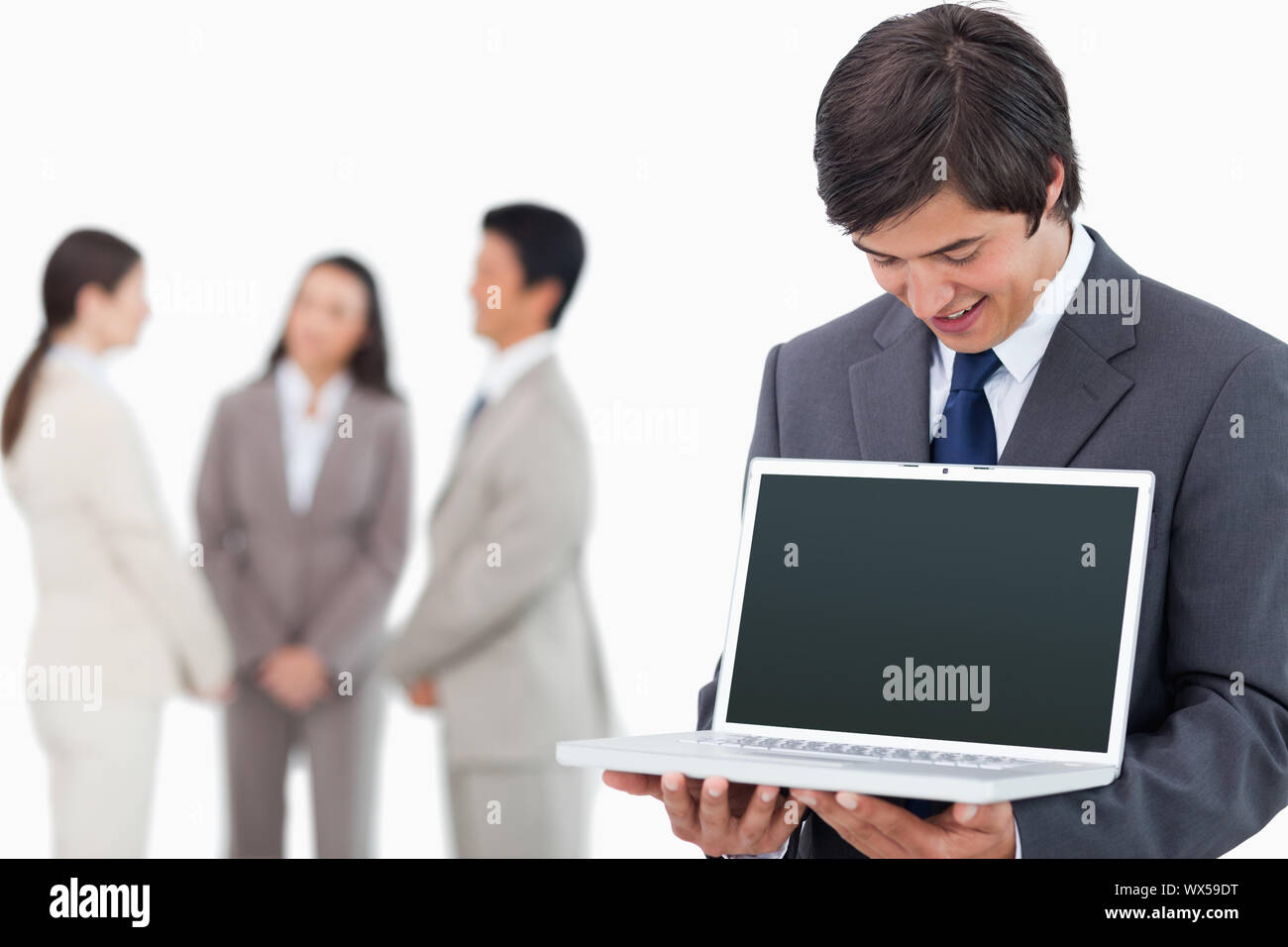 Salesman showing laptop screen with team behind him against a white ...