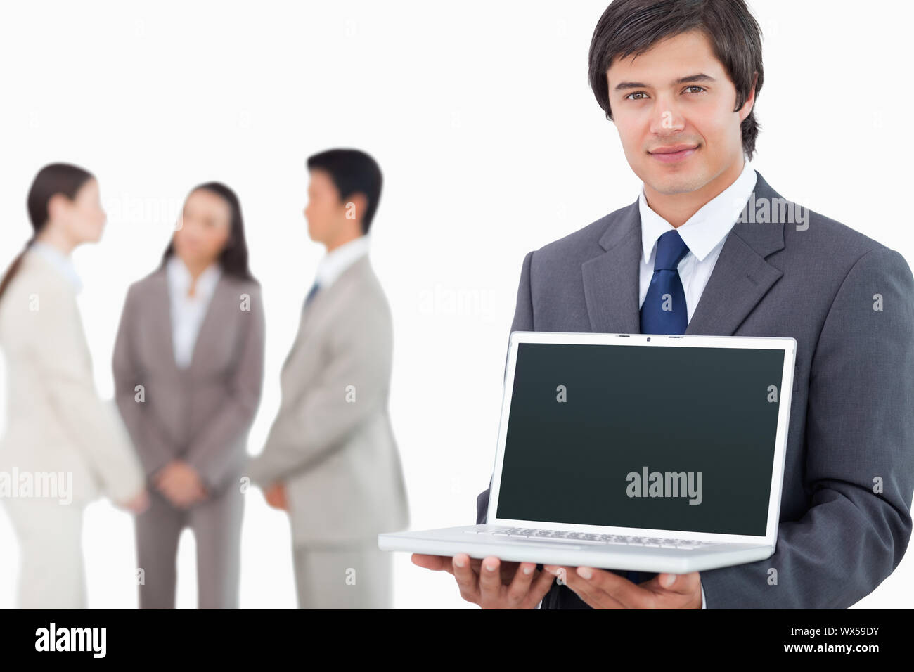 Salesman showing laptop screen with colleagues behind him against a ...