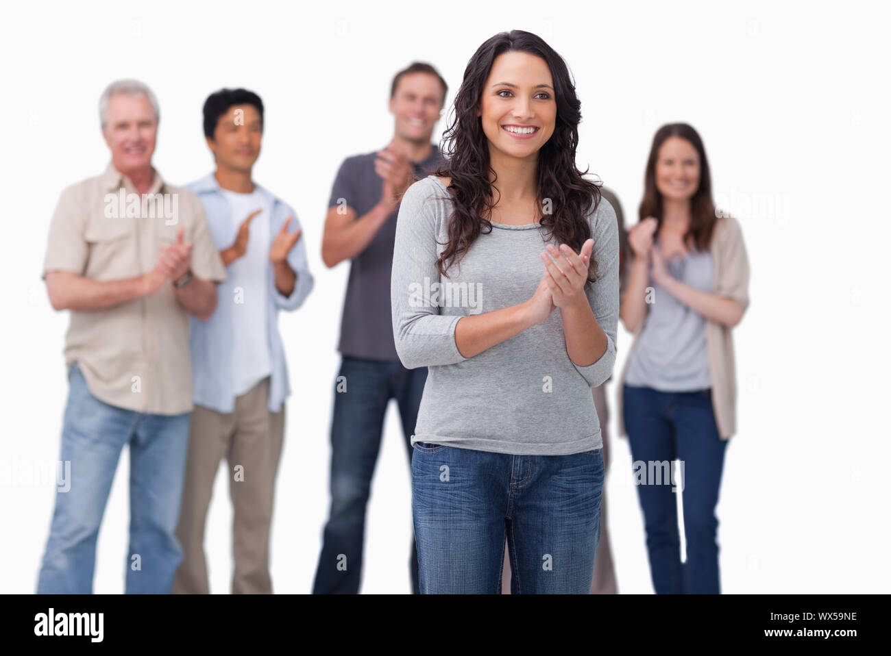 Clapping young woman with friends behind her against a white background ...