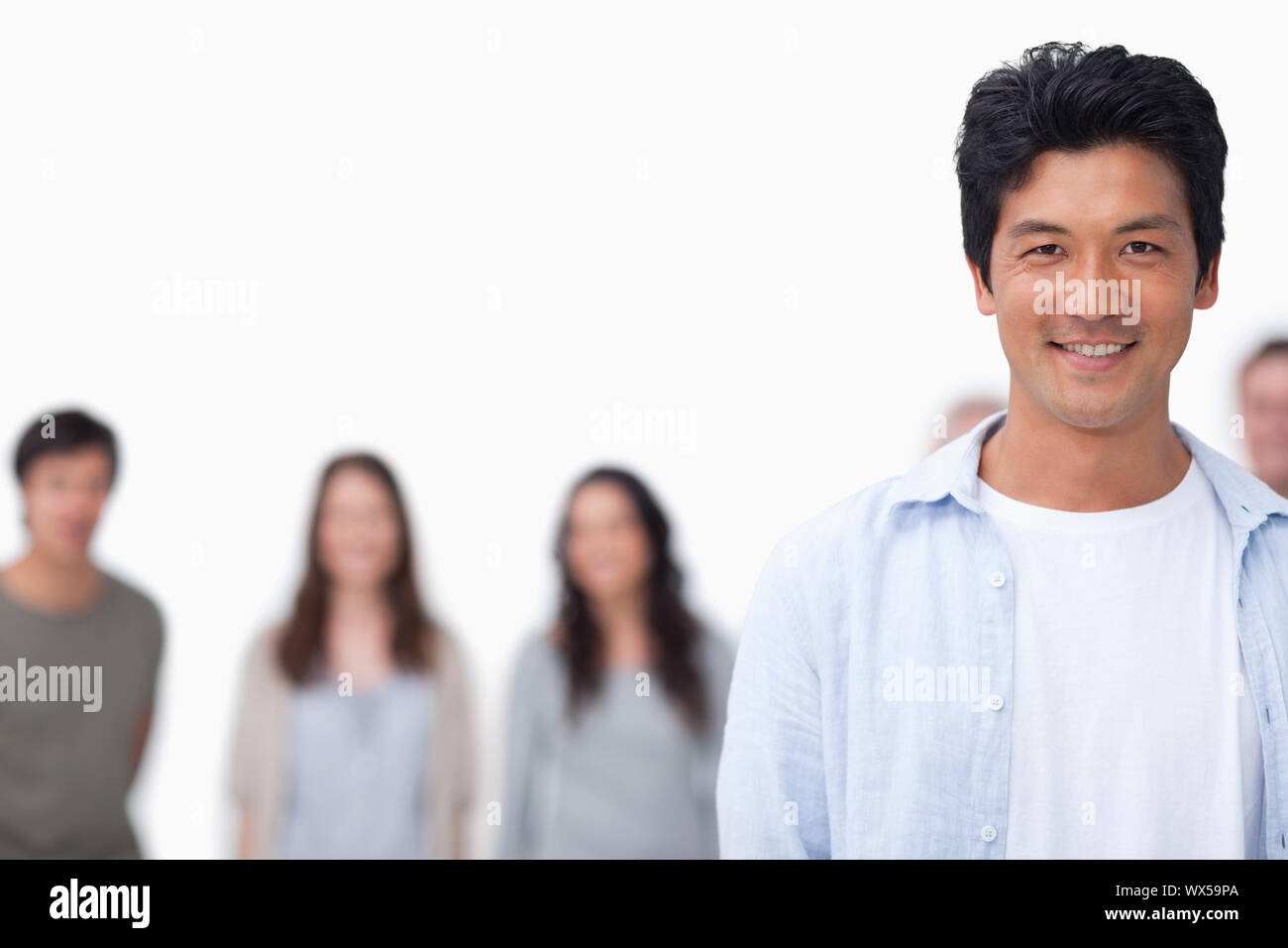Smiling young man with friends standing behind him against a white ...