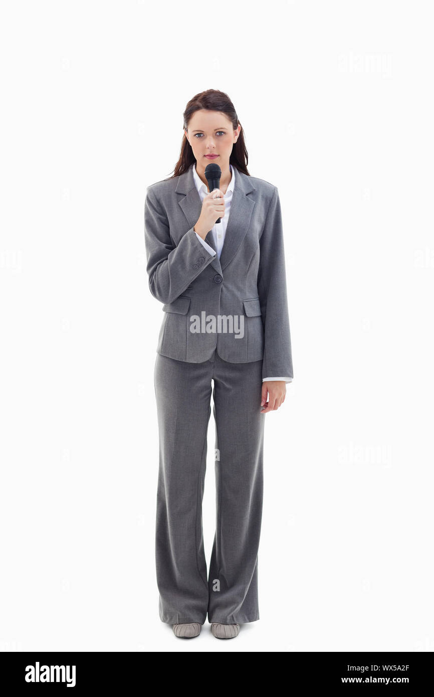Serious businesswoman holding a microphone against white background ...