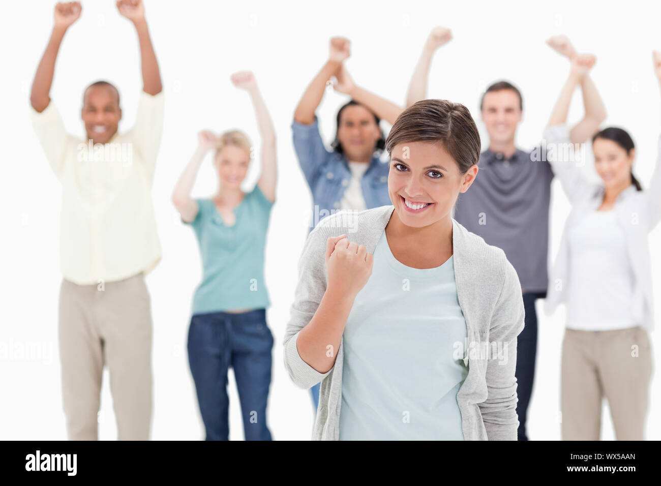 Woman clenching her fist with people behind raising their arms against ...