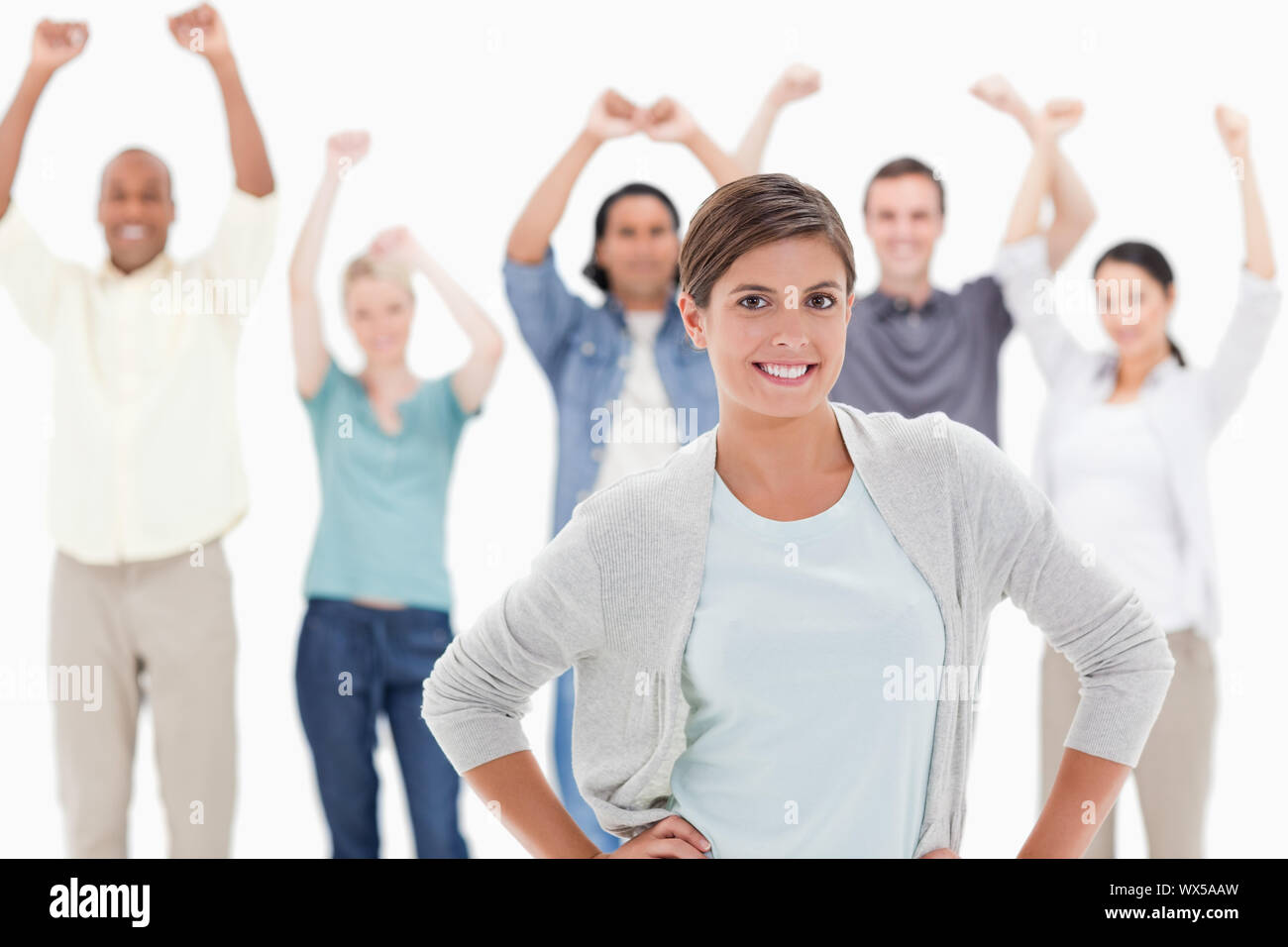 Woman with her hands on hips with people behind raising their arms ...