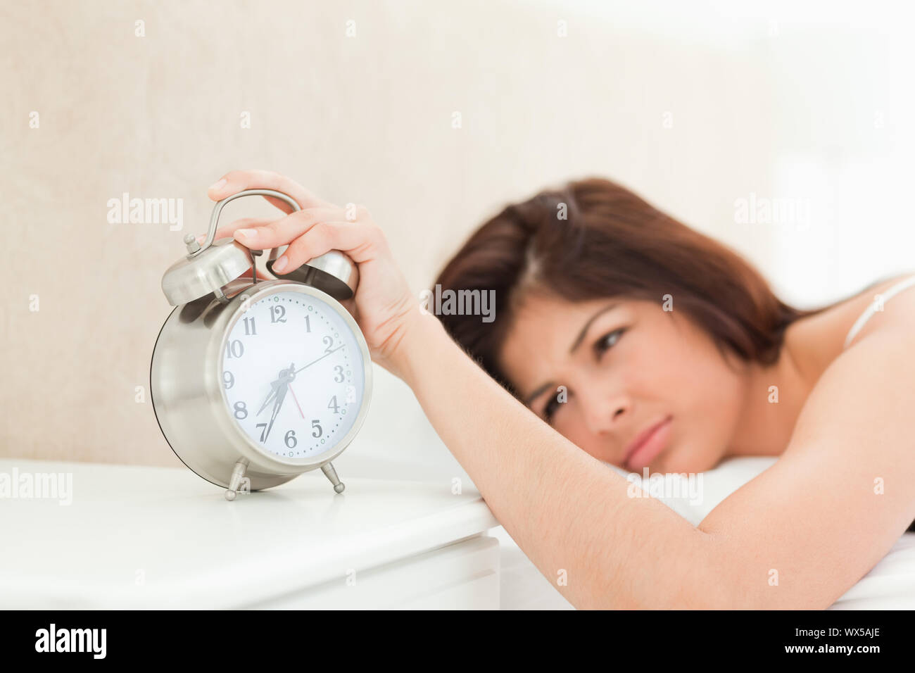 An alarm clock showing the time is being silenced by an awake woman ...