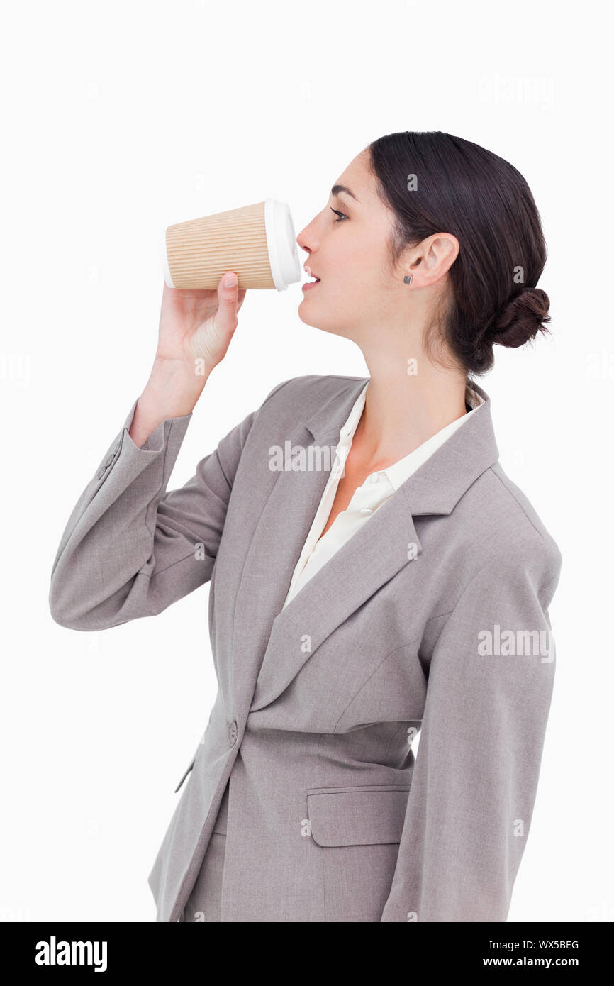 Side view of businesswoman taking a sip out of a paper cup against a ...