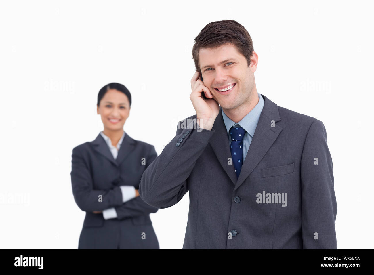 Close up of smiling salesman on the phone with colleague behind her ...