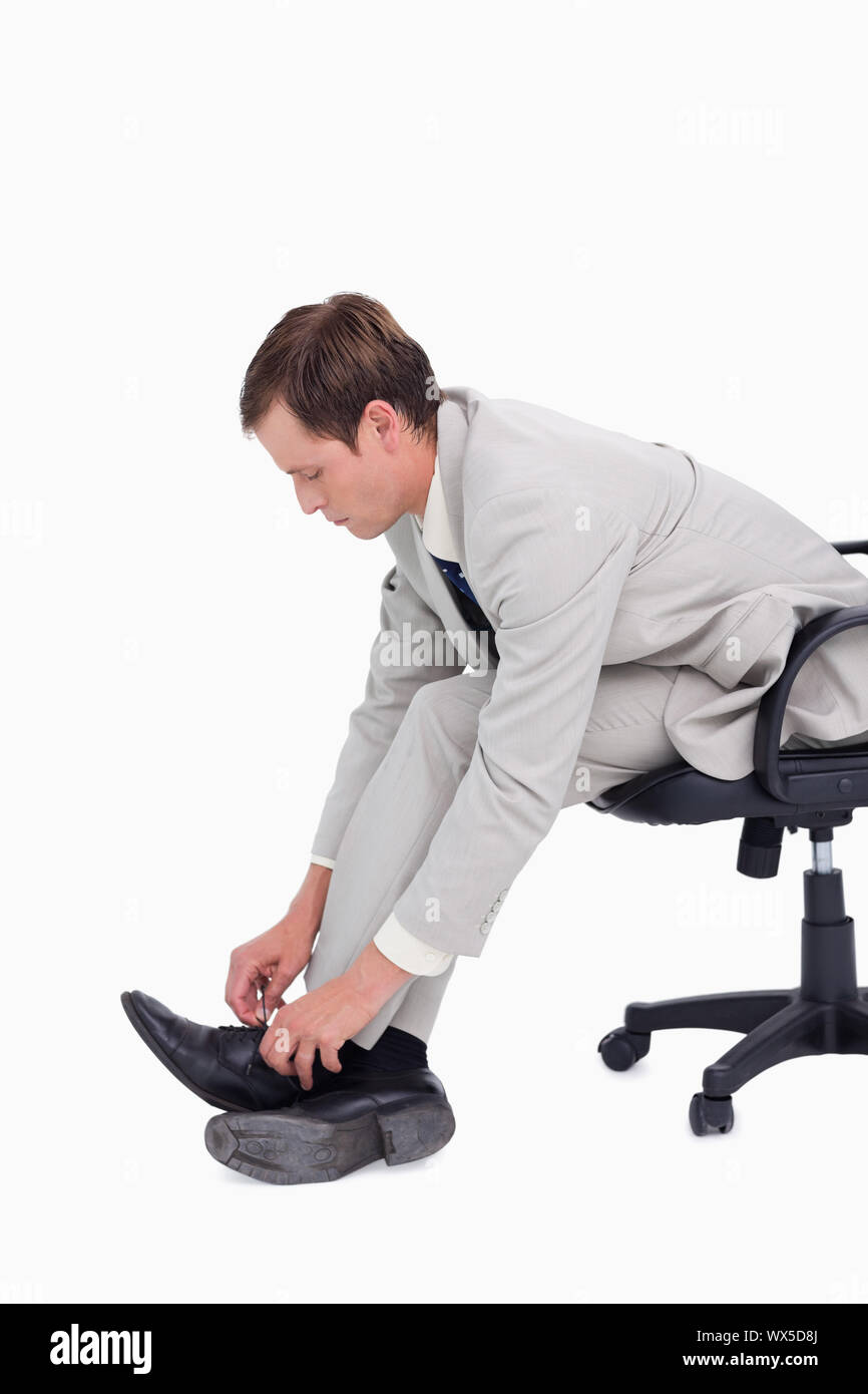 Side view of businessman fastening his shoes Stock Photo - Alamy