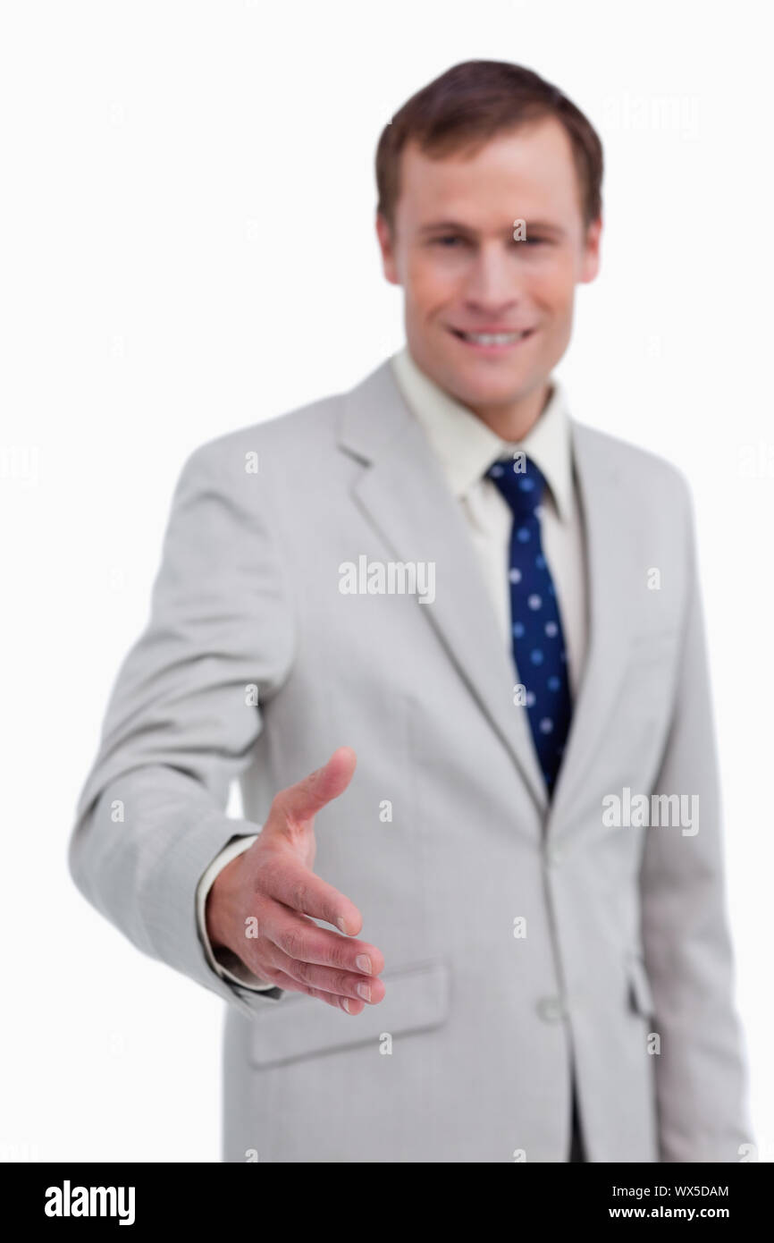 Hand being offered by smiling businessman against a white background ...