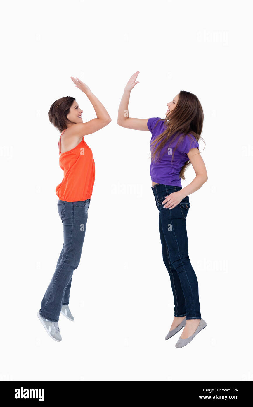 Two teenagers leaping while giving a high-five in the air Stock Photo ...