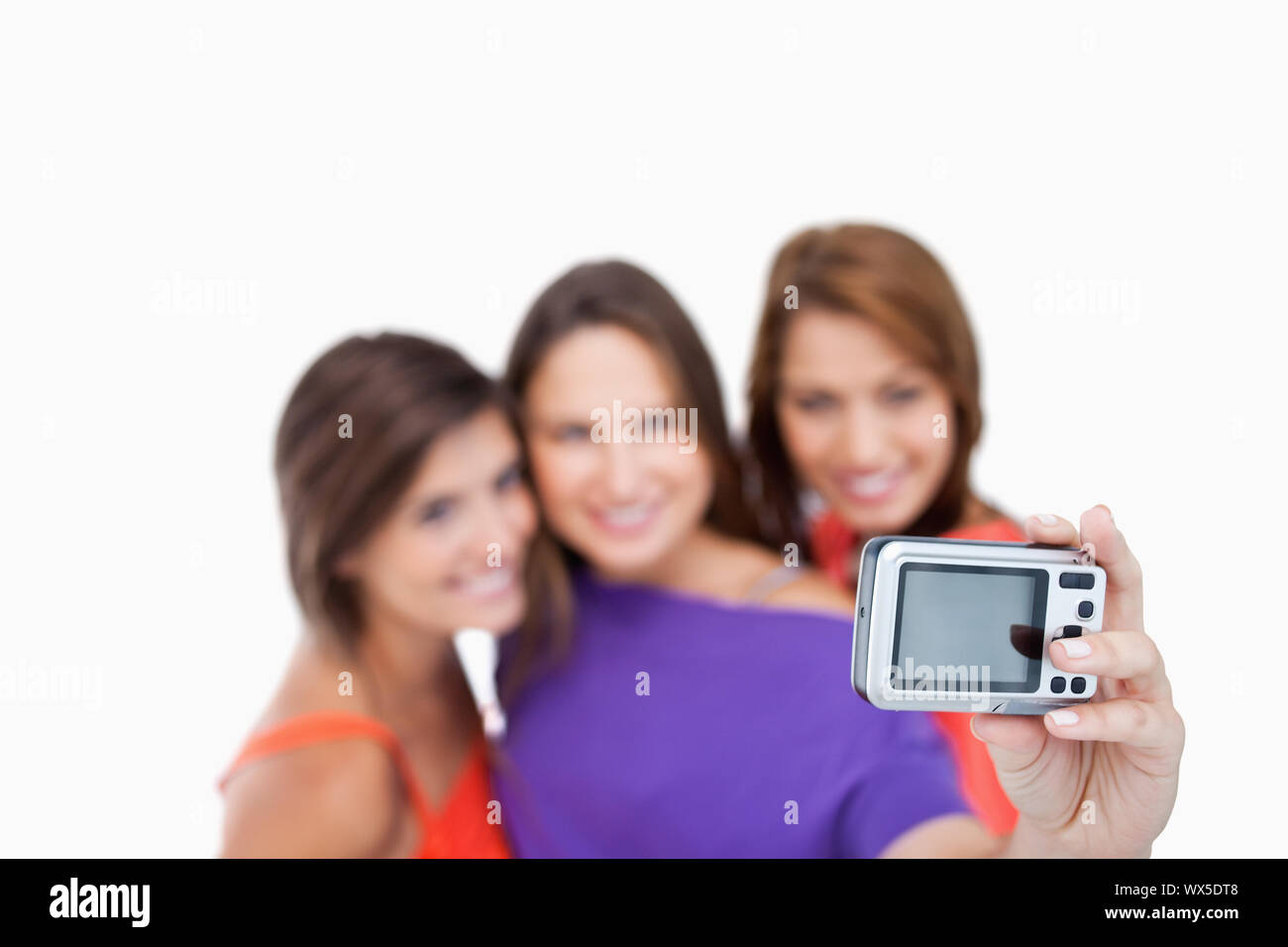 Digital camera held by a teenager photographing three friends with ...