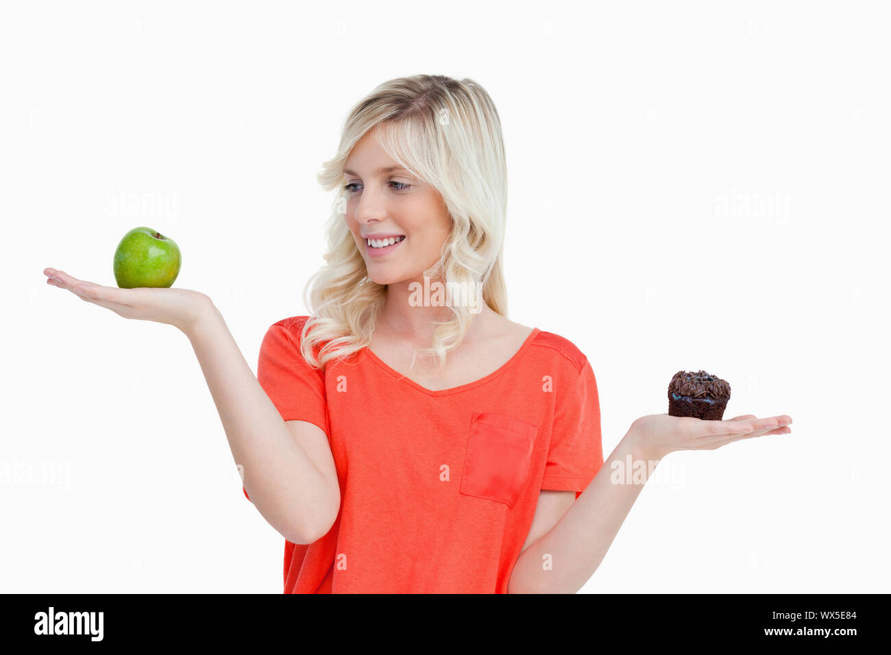 Young woman imitating a balance to choose between a fruit and chocolate ...
