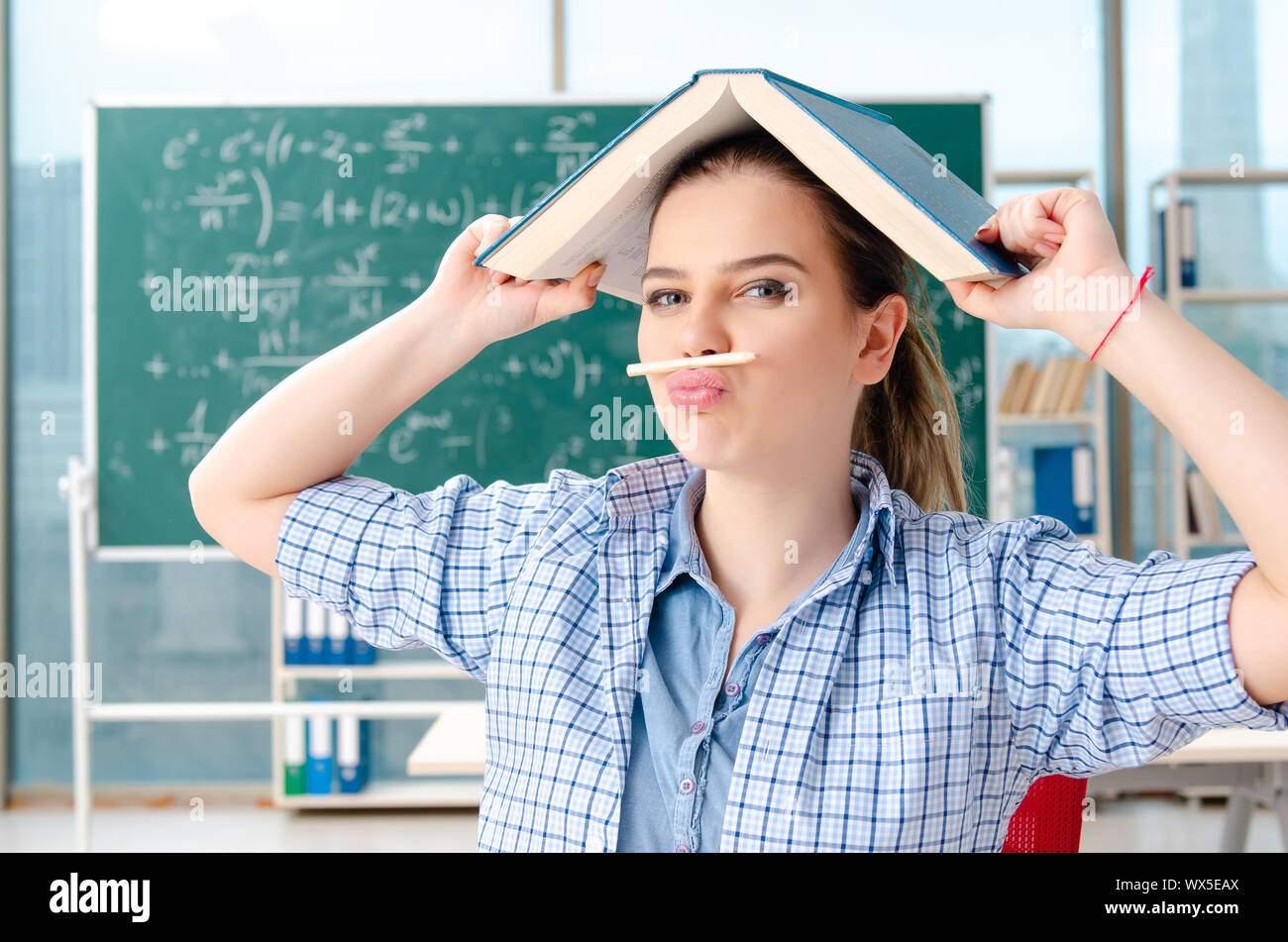 Female student with many books sitting in the classroom Stock Photo - Alamy