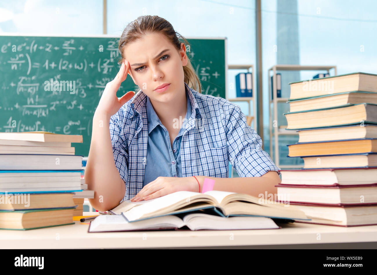 Female student with many books sitting in the classroom Stock Photo - Alamy