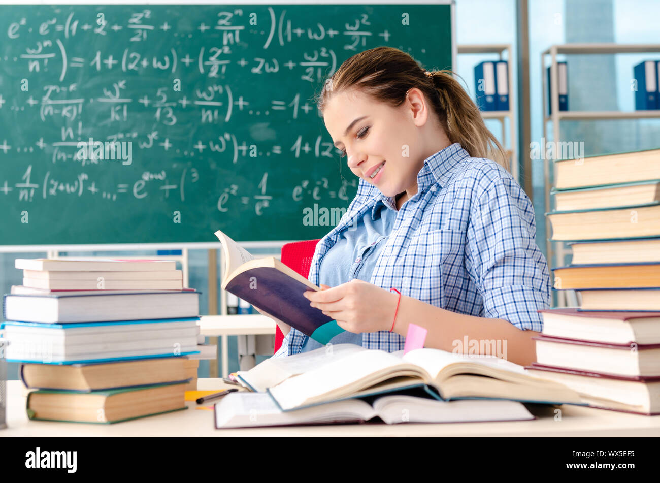 Female student with many books sitting in the classroom Stock Photo - Alamy